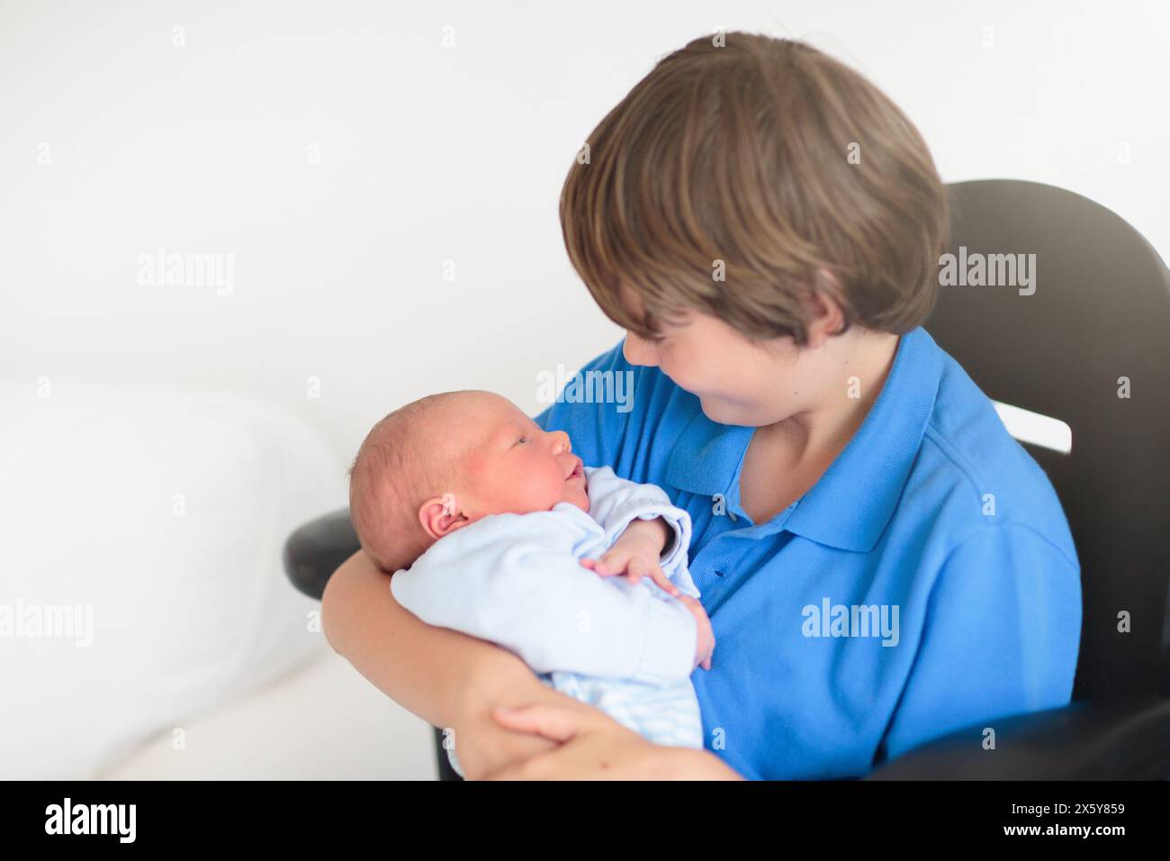 Happy laughing boy holding his sleeping newborn baby brother. Siblings ...