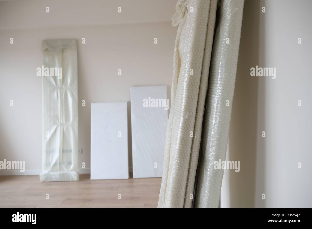 An empty room with hardwood flooring and wrapped in plastic Stock Photo ...