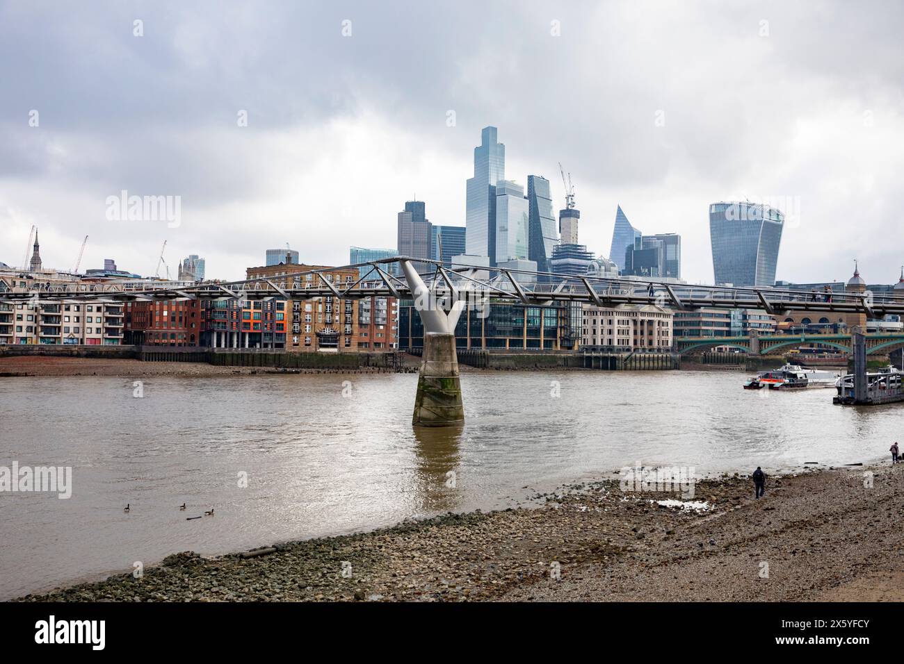 River Thames at low tide with people walking along the bank of the ...