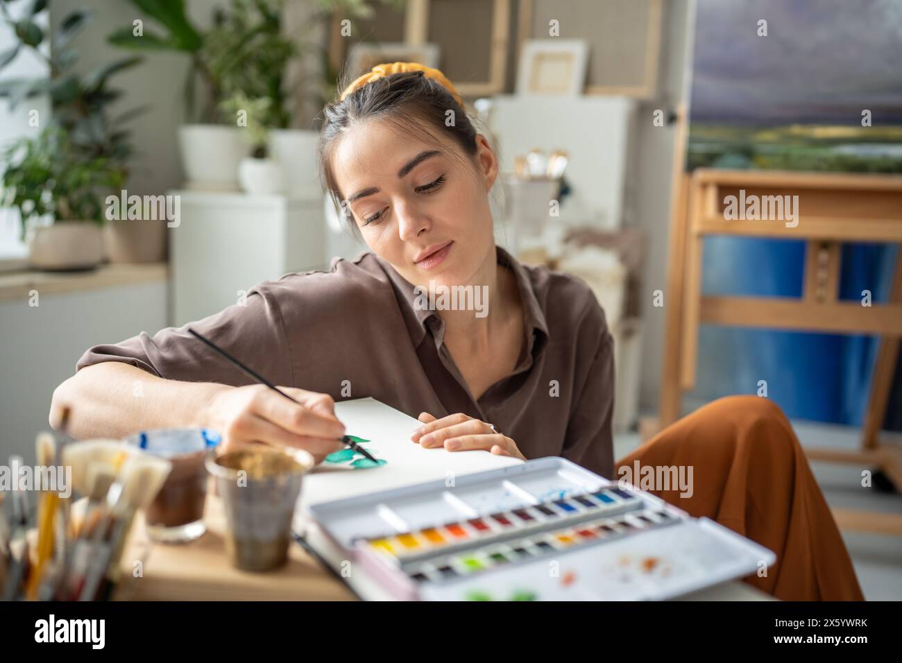 Thoughtful female artist painting with watercolor. Creative painter at ...