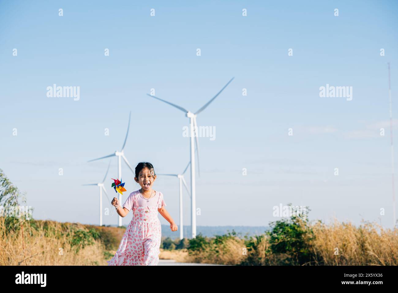 Child's playful exploration by windmills, little girl runs with ...