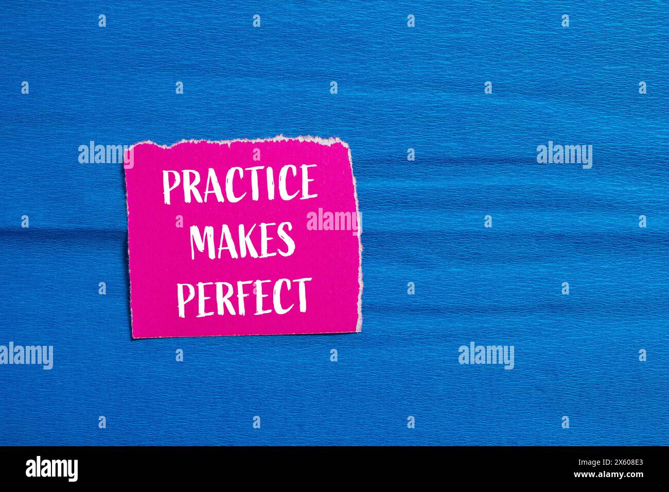 Practice makes perfect words written on ripped pink paper with blue ...