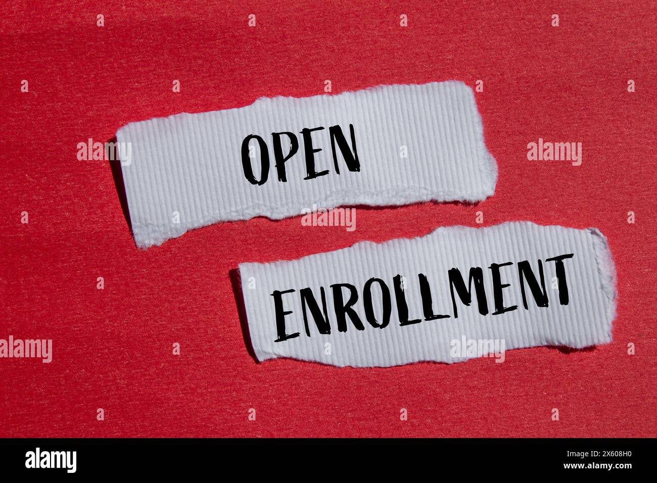 Open enrollment words written on ripped white paper pieces with red ...