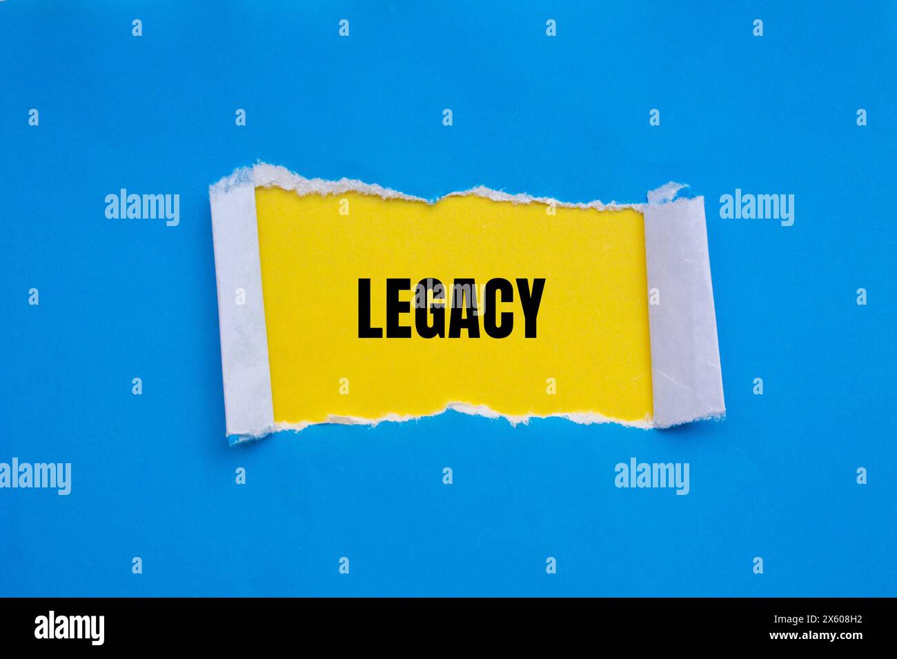 Legacy word written on ripped blue paper with yellow background ...