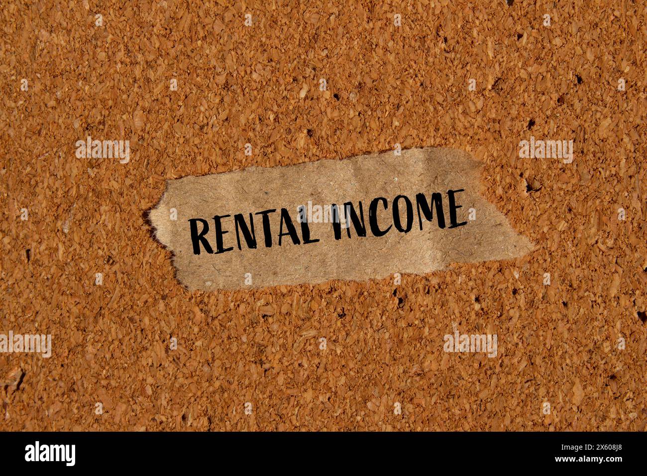 Rental income words written on ripped paper piece with brown background ...