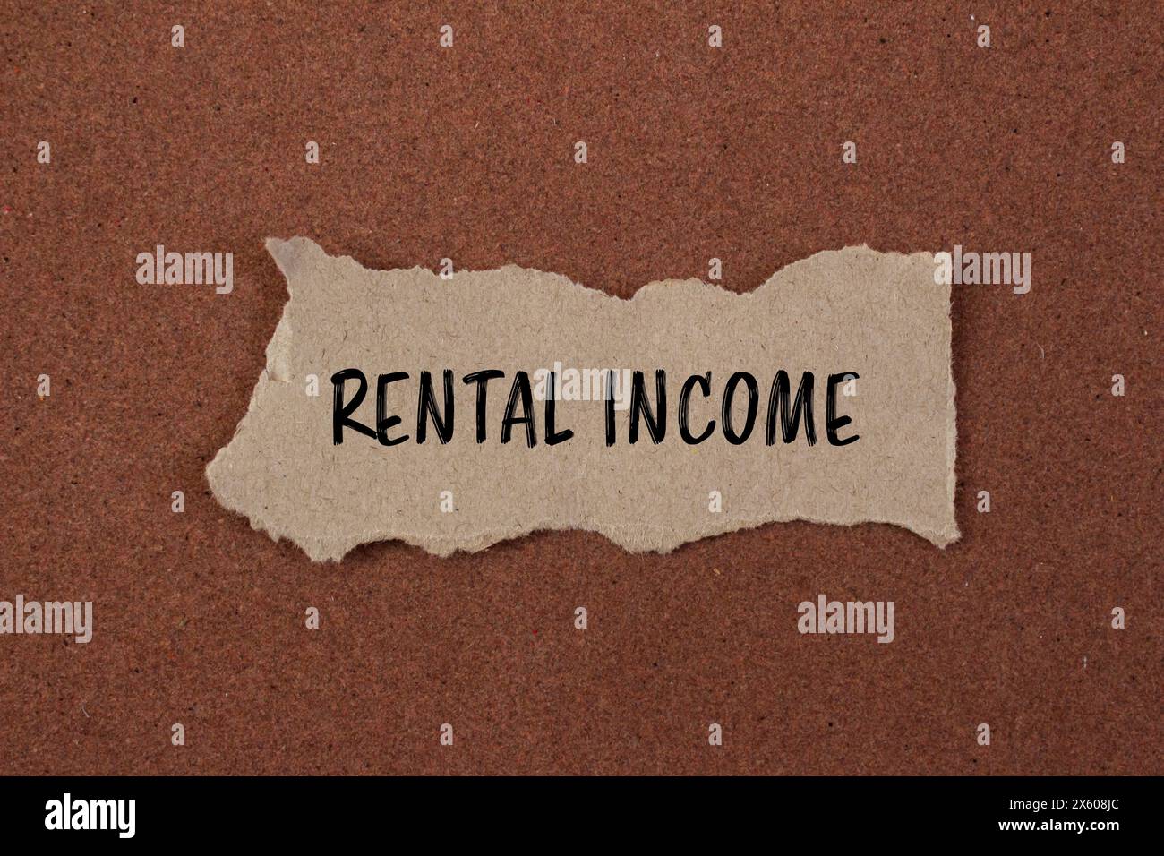 Rental income words written on ripped paper piece with brown background ...