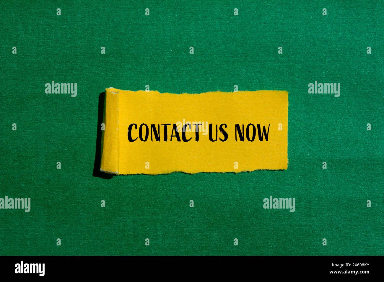 Contact us now words written on ripped yellow paper with green ...