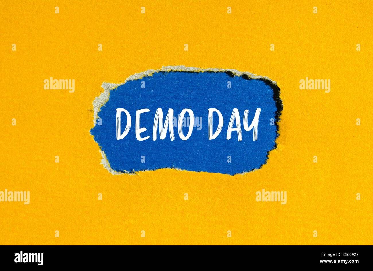 Demo day words written on ripped yellow paper with blue background ...