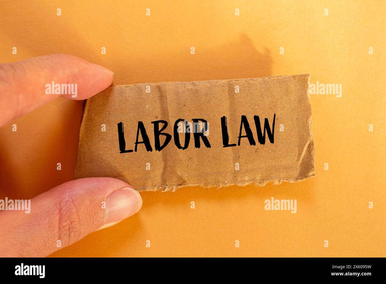 Labor law words written on ripped cardboard paper with orange ...