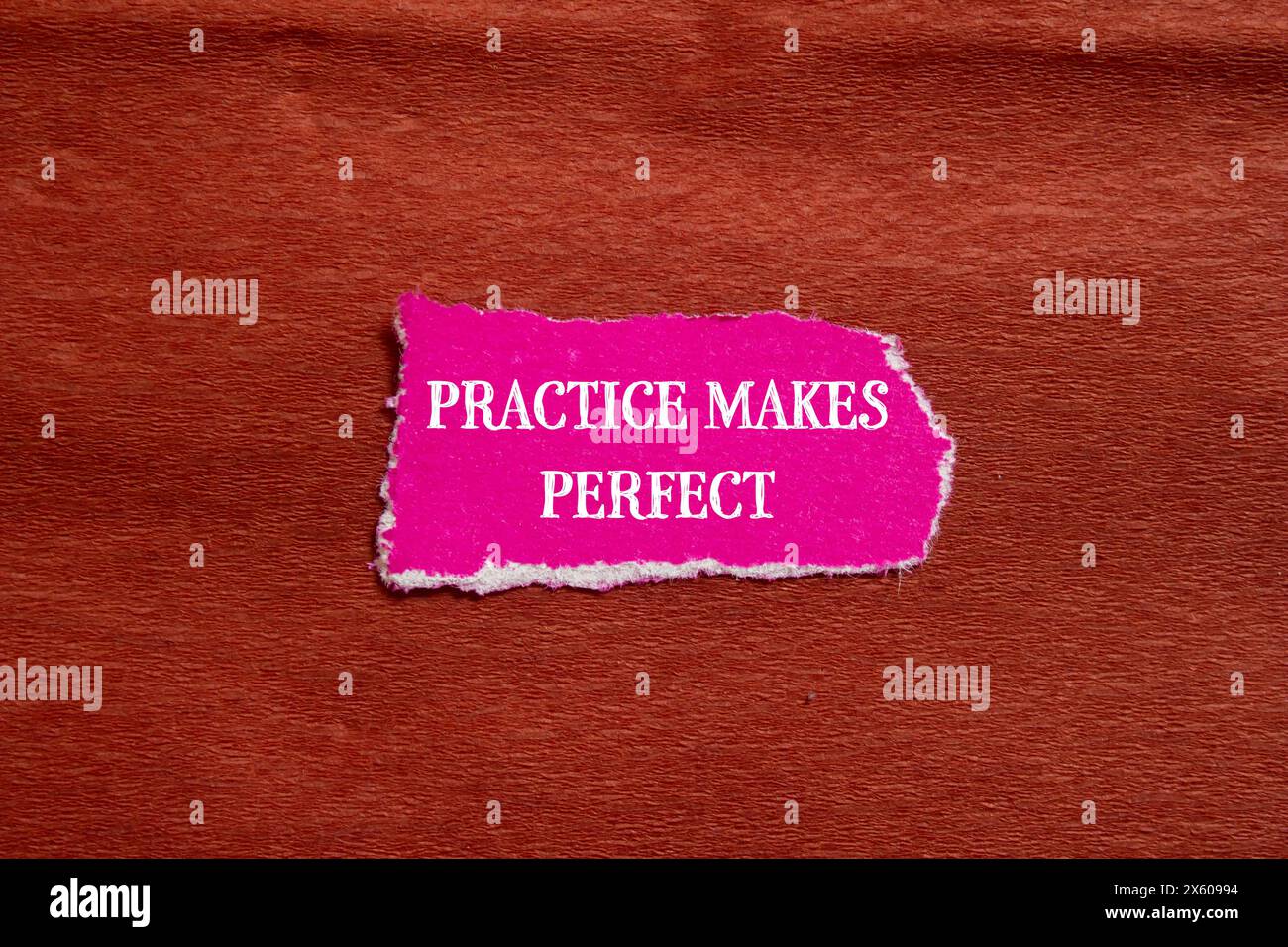 Practice makes perfect words written on ripped pink paper with brown ...
