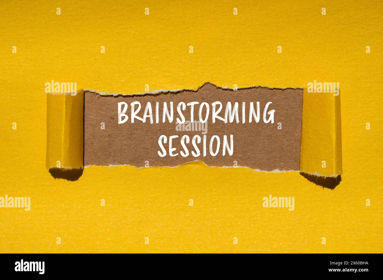 Brainstorming session words written on ripped yellow paper with brown ...