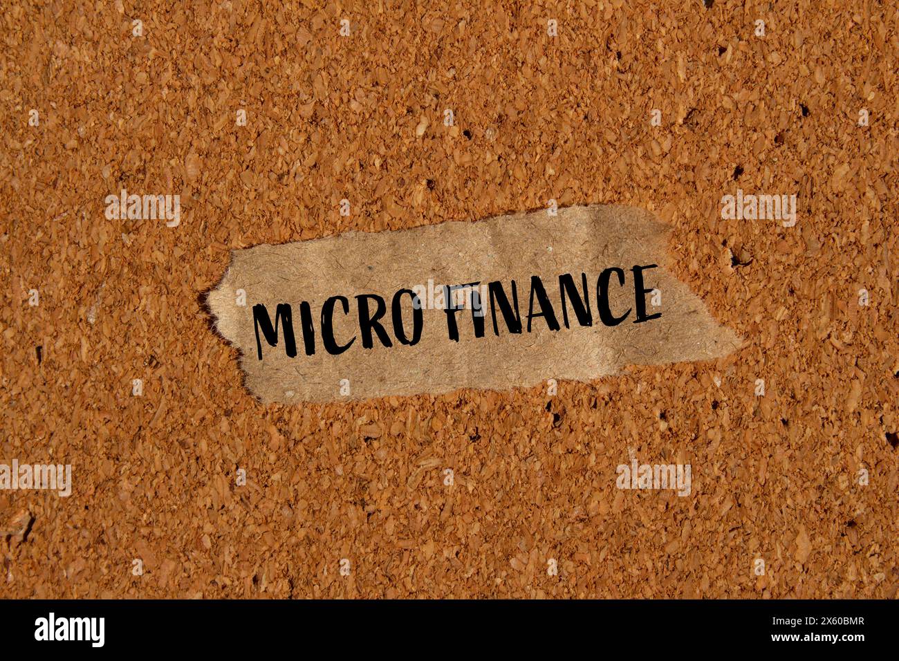 Micro finance words written on ripped paper piece with brown background ...