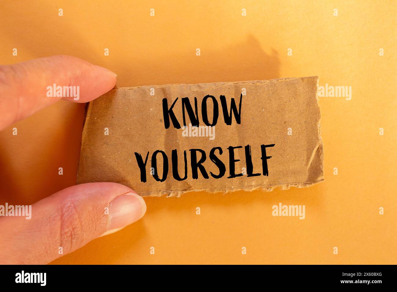 Know yourself words written on ripped cardboard paper with orange ...