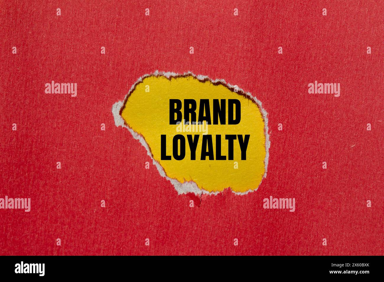 Brand loyalty words written on ripped red paper with yellow background ...