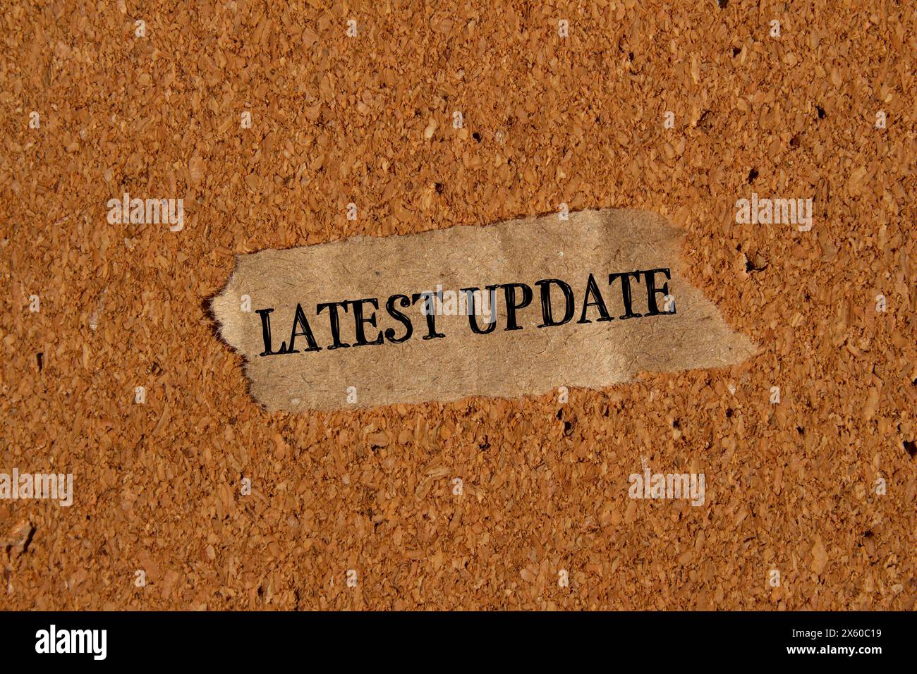 Latest update words written on ripped paper piece with brown background ...