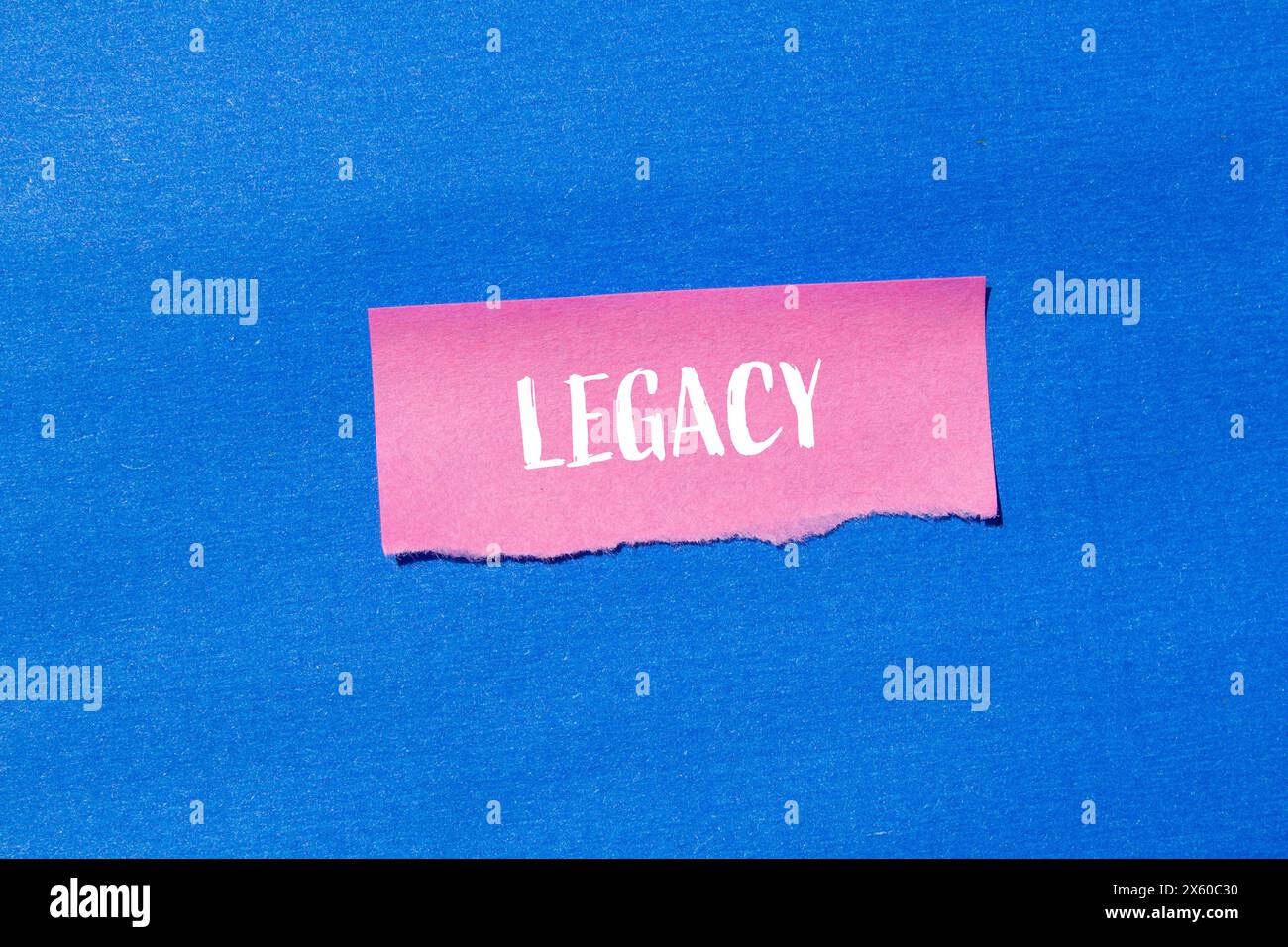 Legacy word written on ripped pink paper with blue background ...