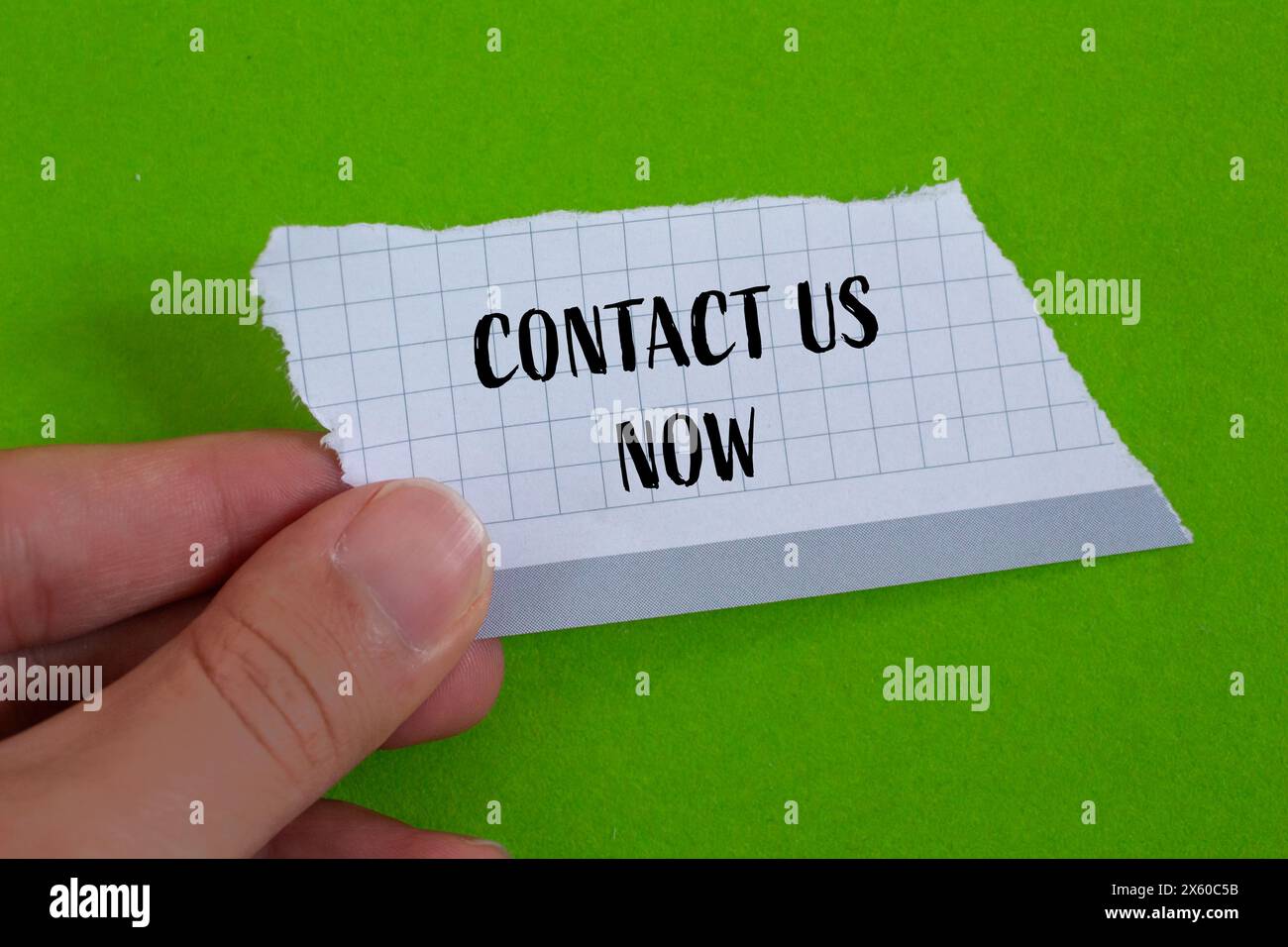 Contact us now words written on ripped paper with green background ...