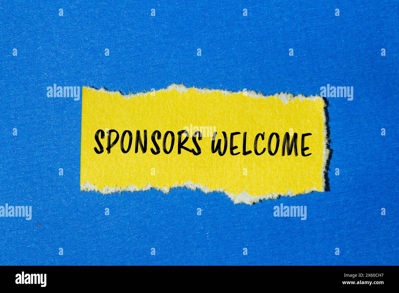 Sponsors welcome words written on ripped yellow paper piece with blue ...