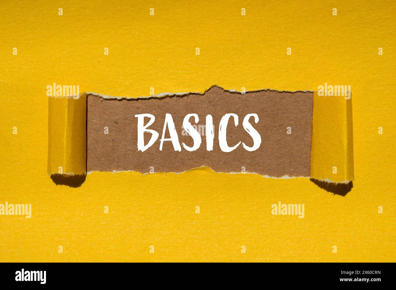 Basics word written on ripped yellow paper with brown background ...