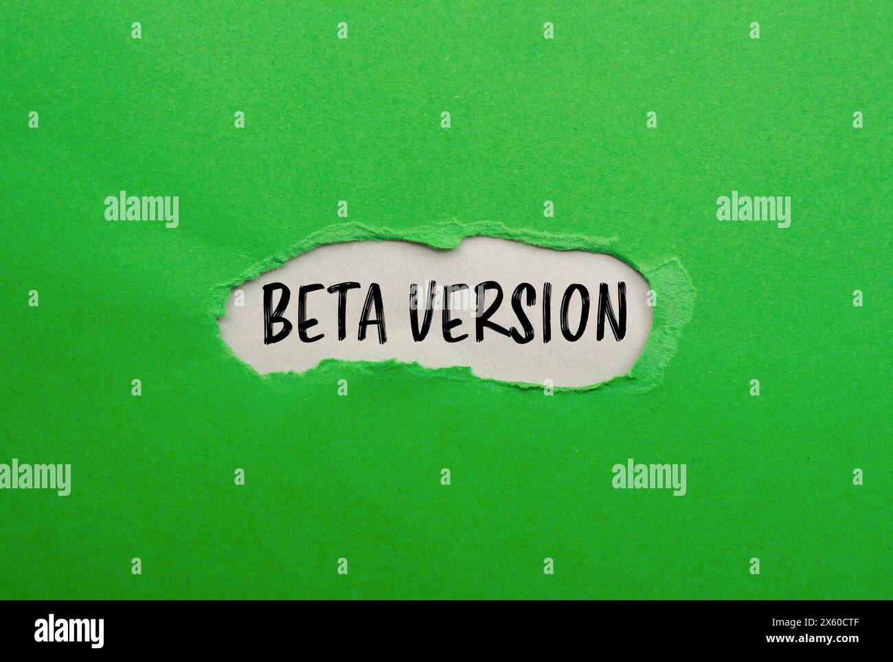 Beta version words written on ripped green paper with gray background ...