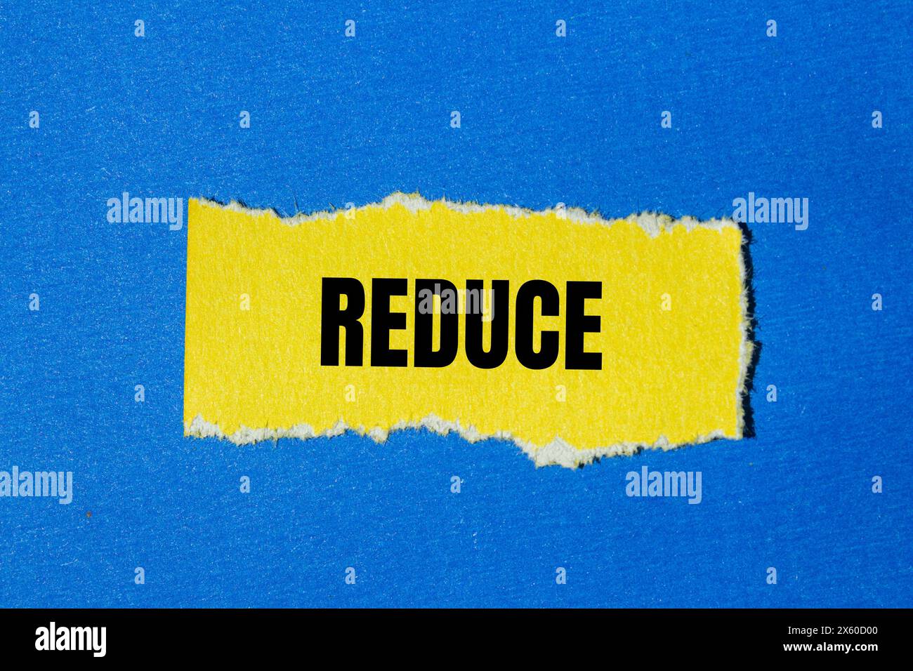 Reduce word written on ripped yellow paper with blue background ...