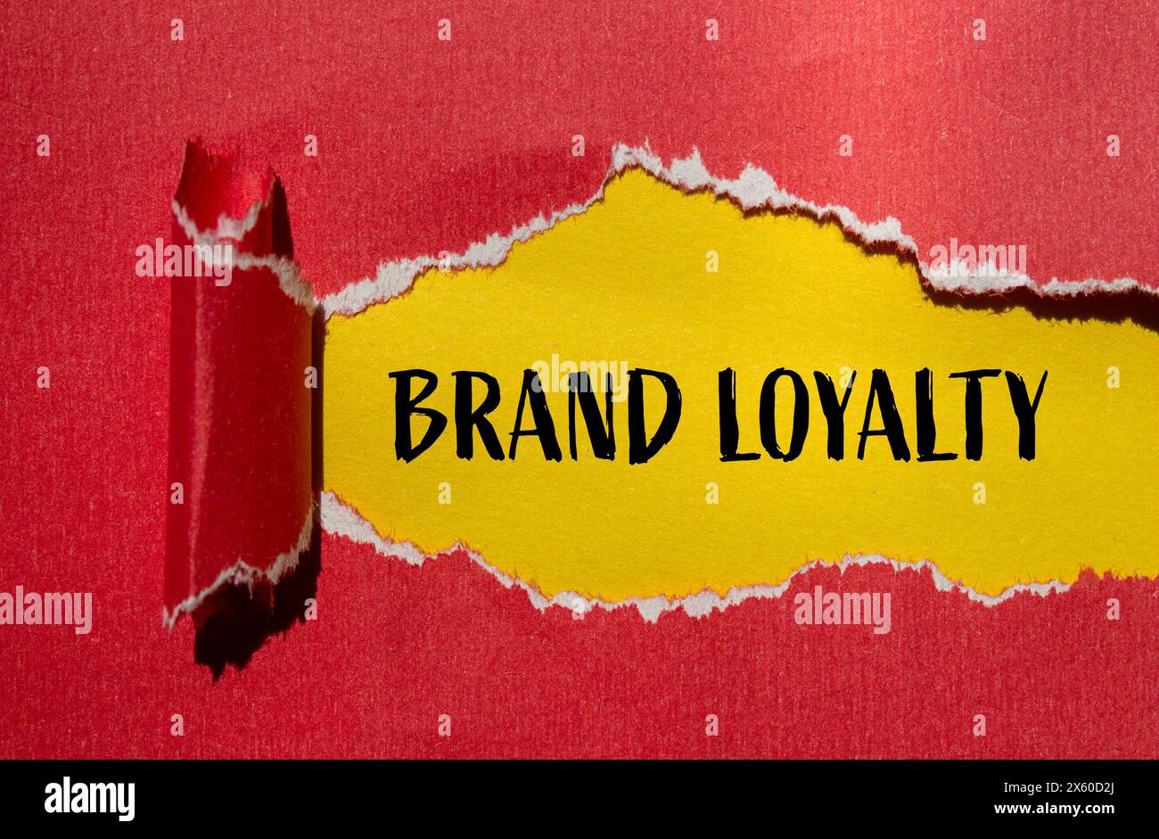 Brand loyalty words written on ripped red paper with yellow background ...