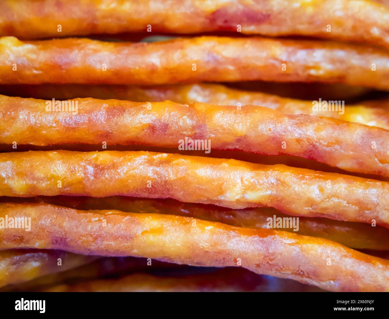 A close up of a row of meat sticks. The sticks are brown and have a ...