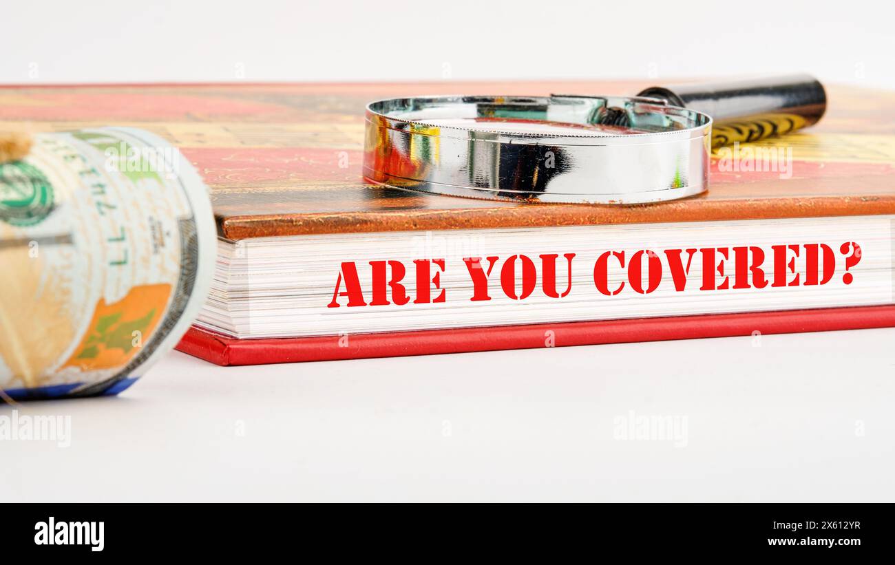 ARE YOU COVERED text written on the pages of the book next to a roll of ...