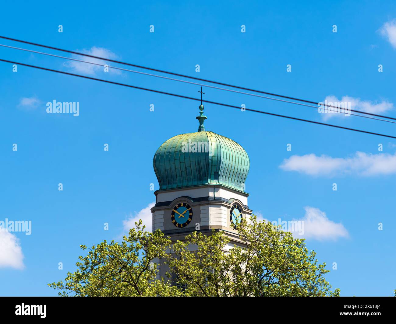 Copper-domed church bell tower against a blue sky with a small cross ...