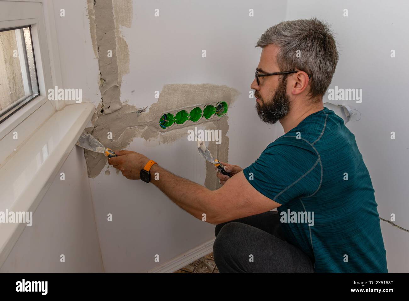 the man plasters the wall and the electric cable and sockets Stock ...