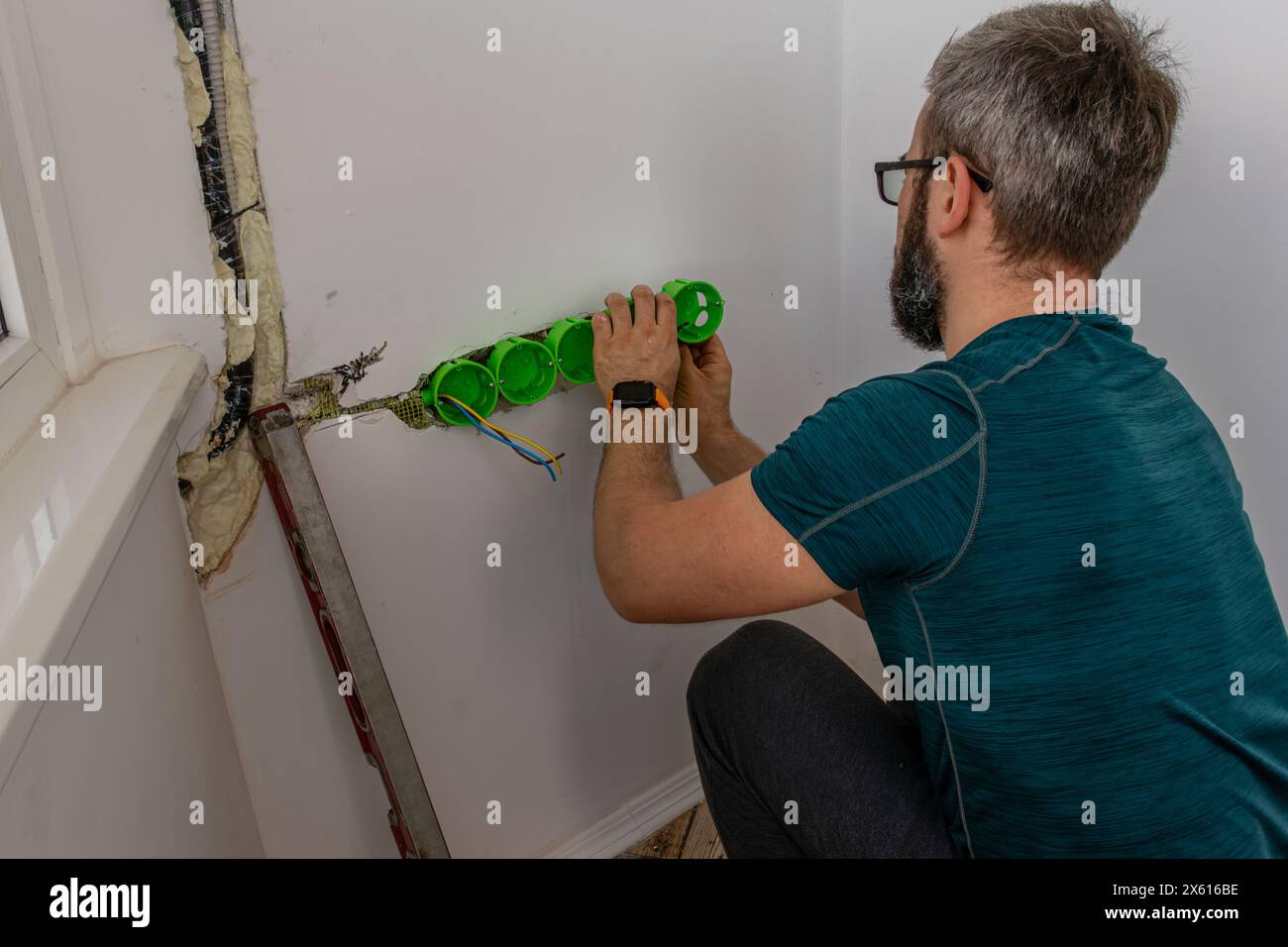 a man mounts wall sockets on plaster Stock Photo - Alamy