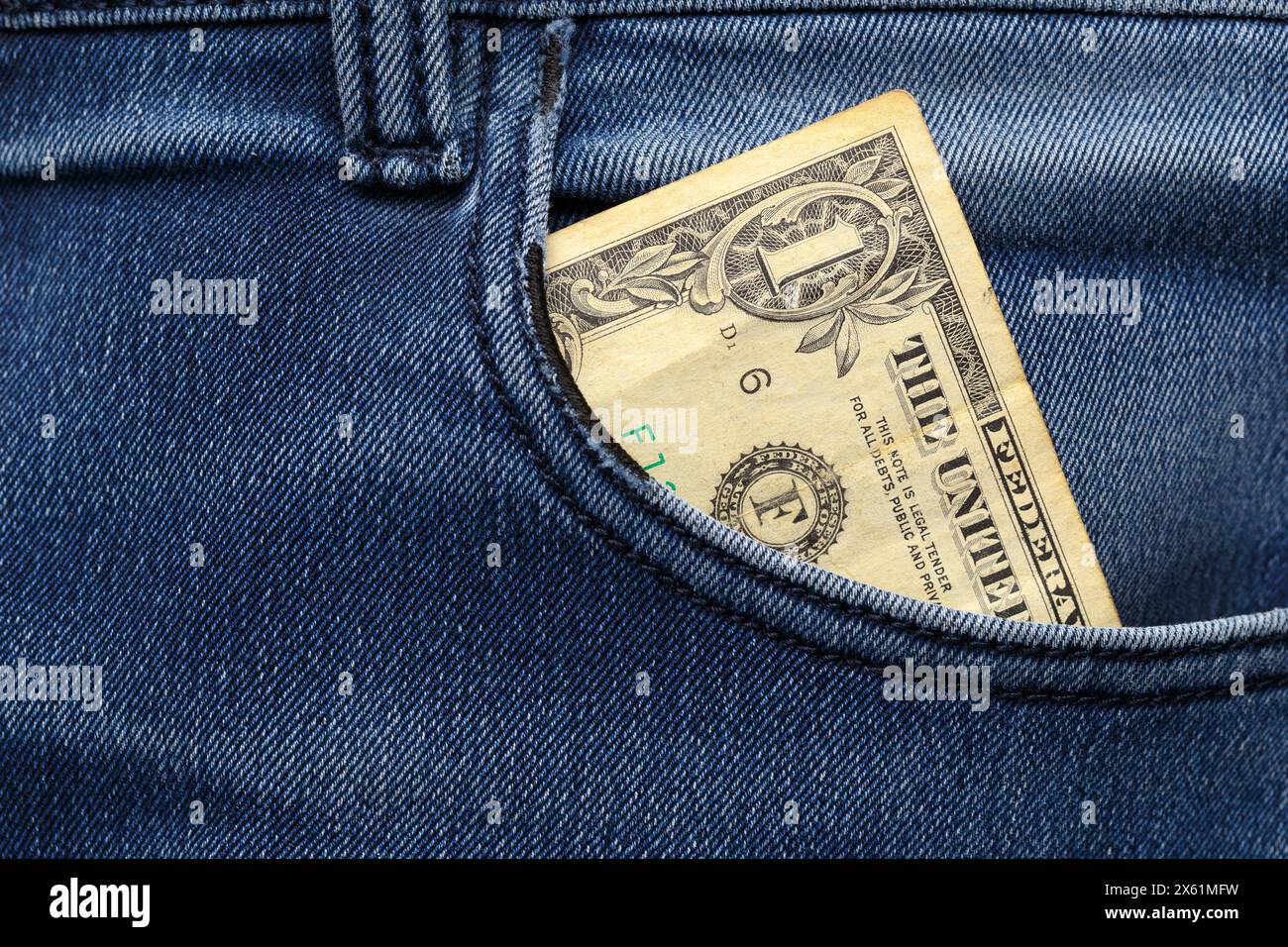 The corner of a one dollar bill sticks out of a blue jeans pocket ...