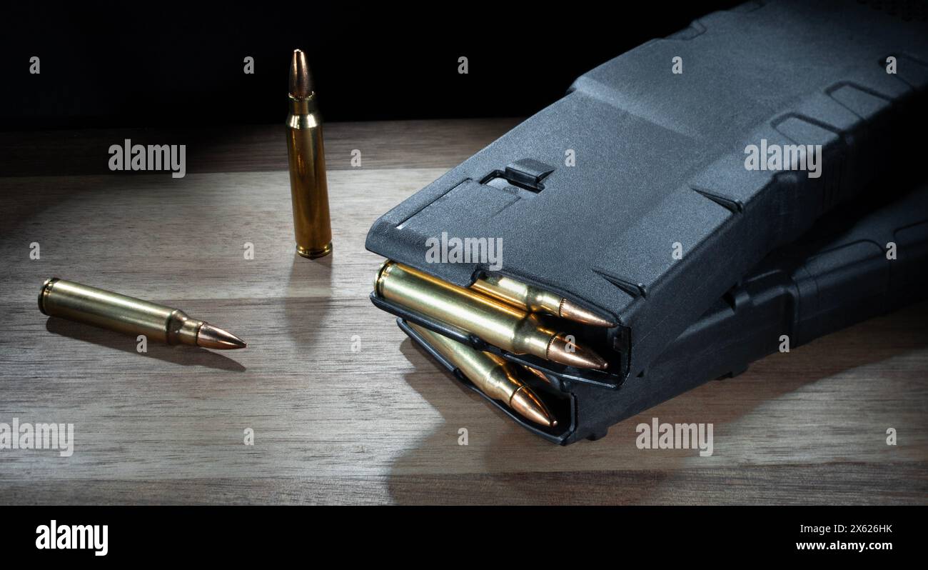 Two cartridges on the table next to AR-15 magazines that are high capacity and fully loaded with ...