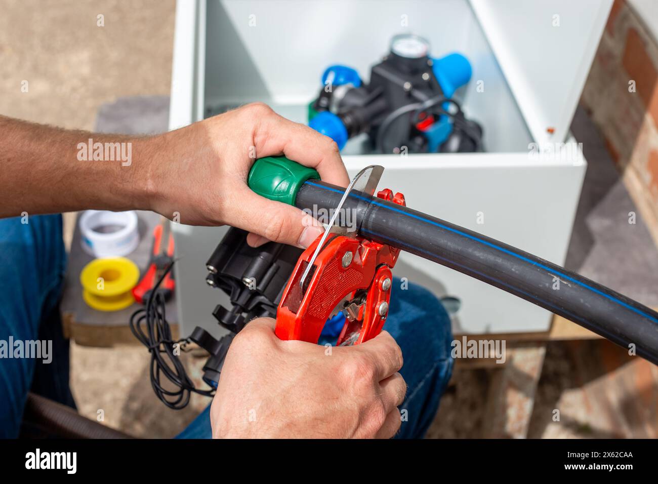 The master installs drip irrigation for the garden. A man cuts off a ...