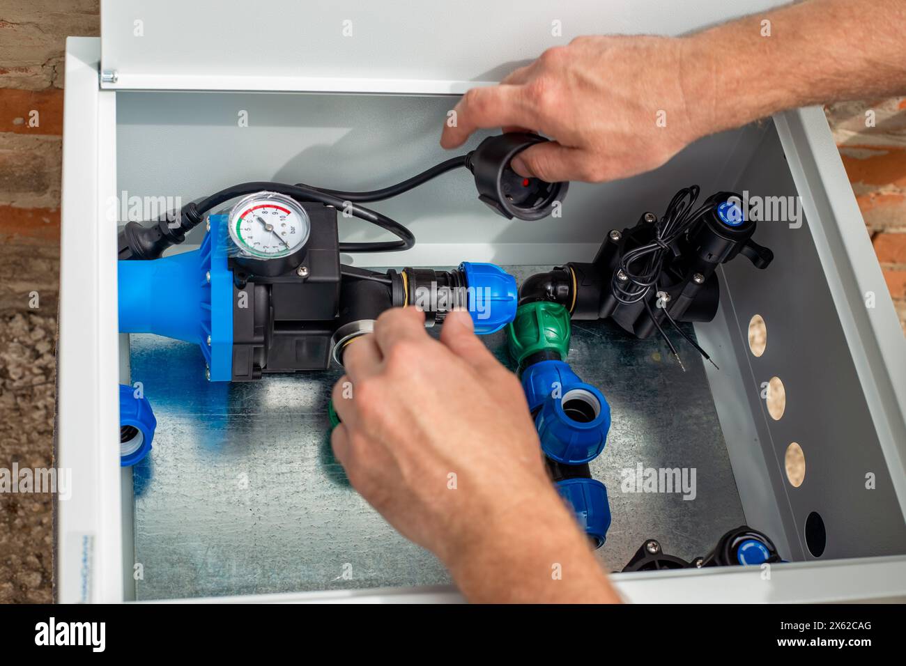 The master installs a drip irrigation system for the garden. A man ...