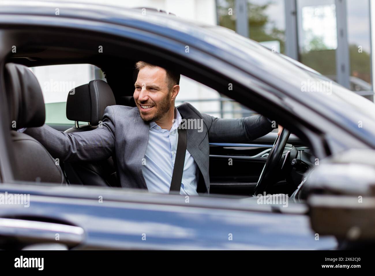 Man beams with happiness as he invites someone to join him in his sleek ...