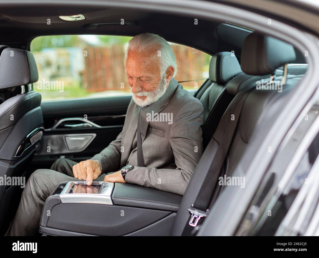 Distinguished older man in a suit adjusts the touchscreen dashboard of ...