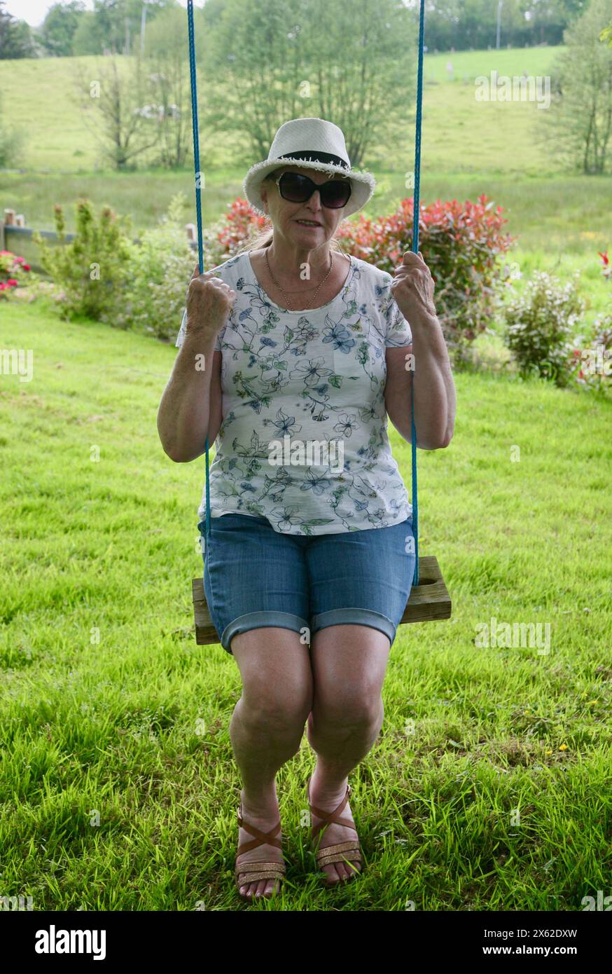 A lady on the garden swing, in the french countryside, Normandy, France ...