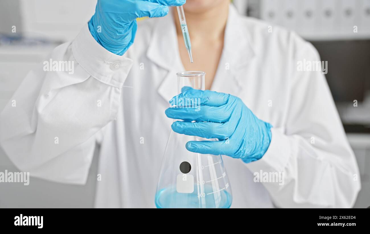 A woman scientist conducts experiments in a laboratory, holding a ...
