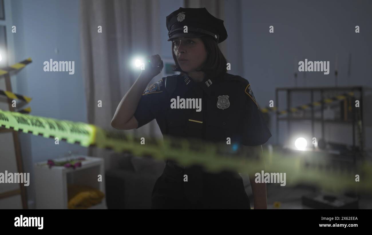 Hispanic policewoman investigates a dimly-lit indoor crime scene ...