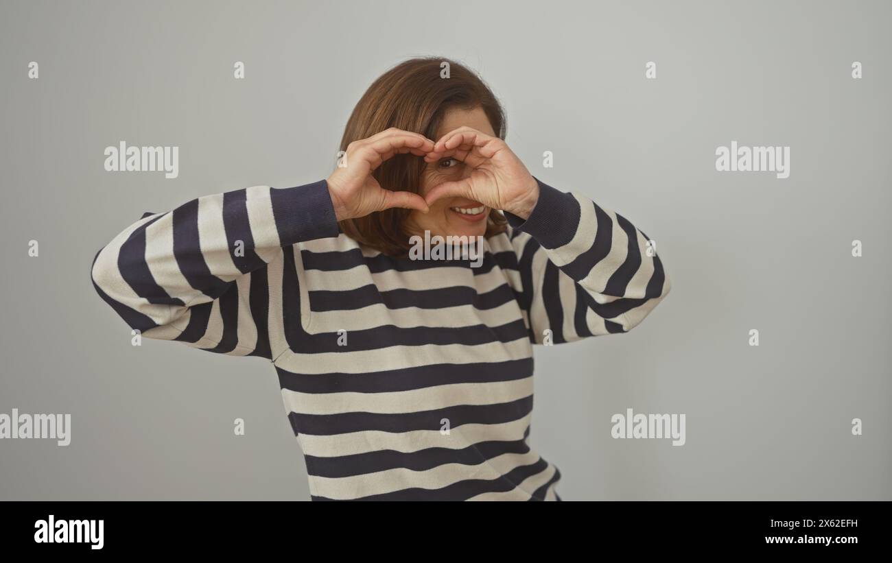 A middle-aged woman forms heart shape with hands, smiling, isolated on ...