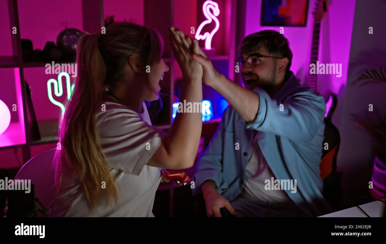 A cheerful couple celebrates a moment in a colorful neon-lit gaming ...