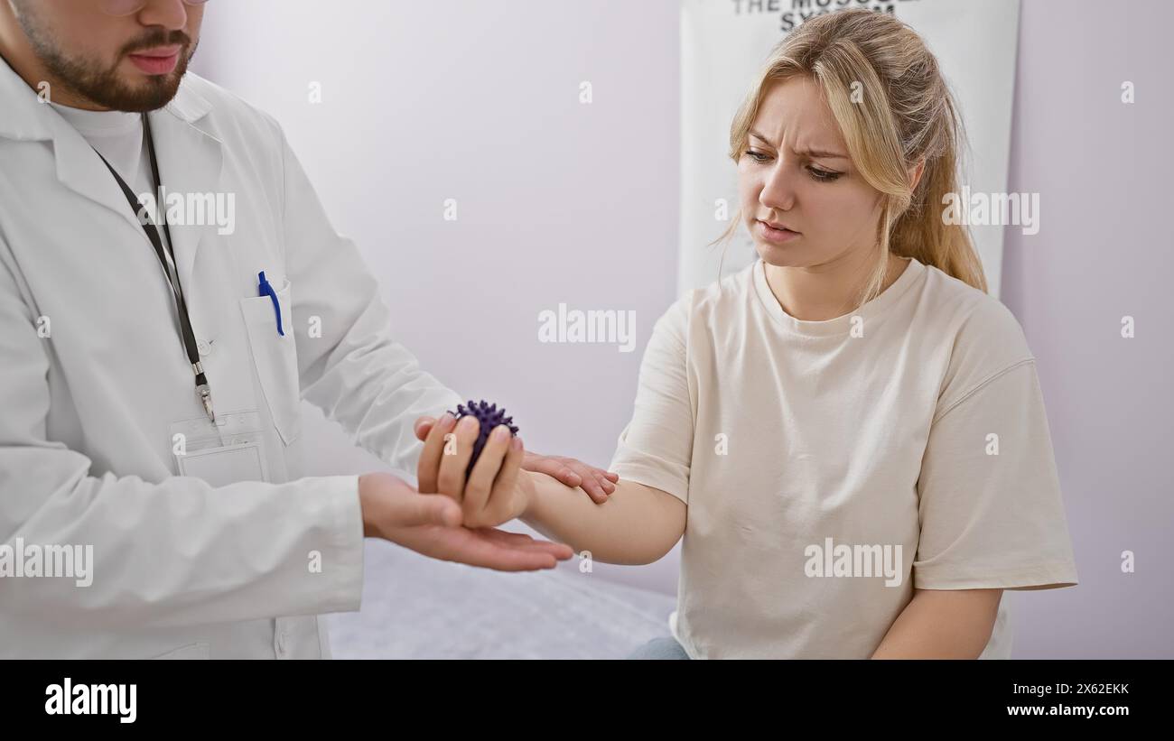 A male physiotherapist in a clinic assesses the arm of a female patient ...