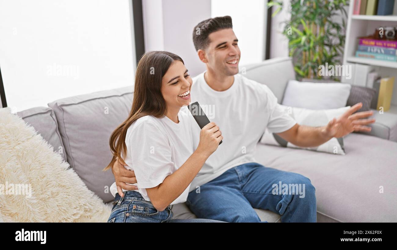 Happy couple singing together on a cozy sofa in a modern living room ...