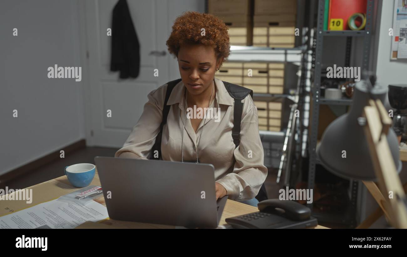 A focused african american woman detective working on a laptop in a ...