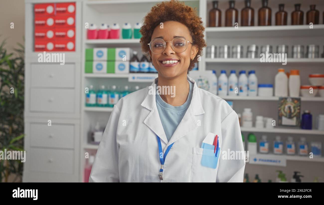 Smiling african american woman pharmacist in white lab coat standing in ...