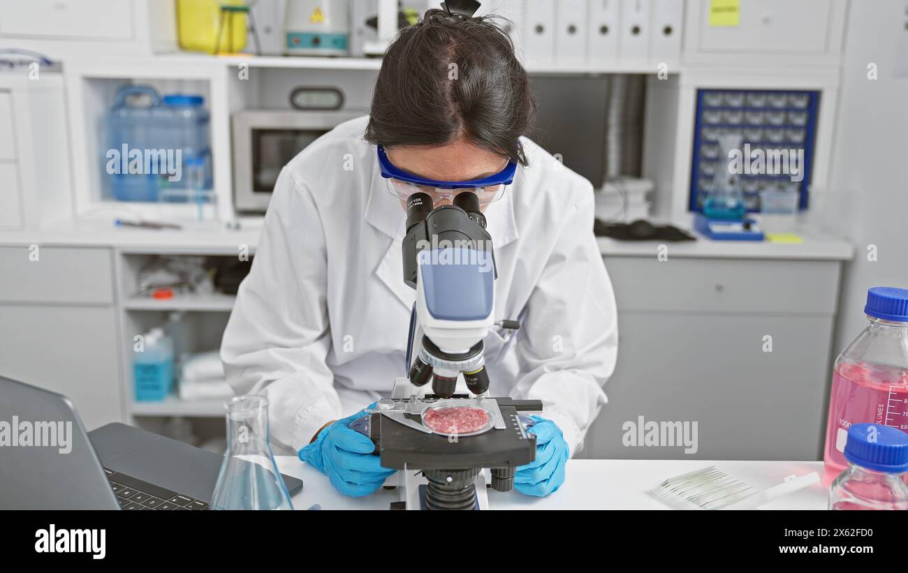 A woman scientist utilizes a microscope in a laboratory setting ...
