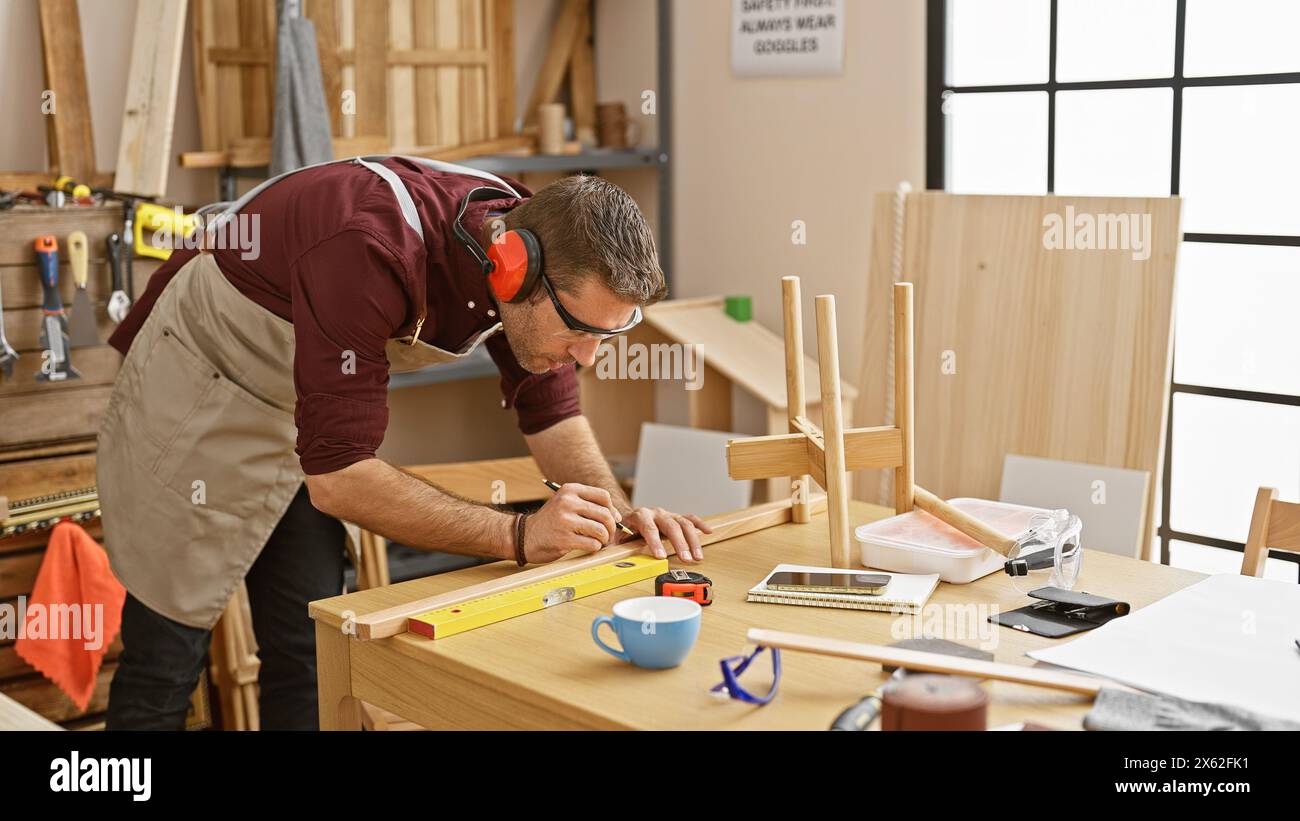 Handsome bearded craftsman using tools in a well-organized woodworking ...