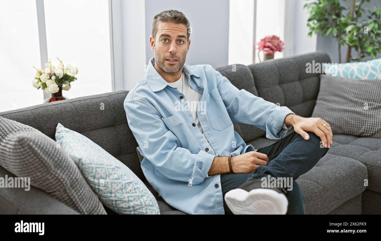 Casual young man with beard lounging on sofa in well-lit modern living ...