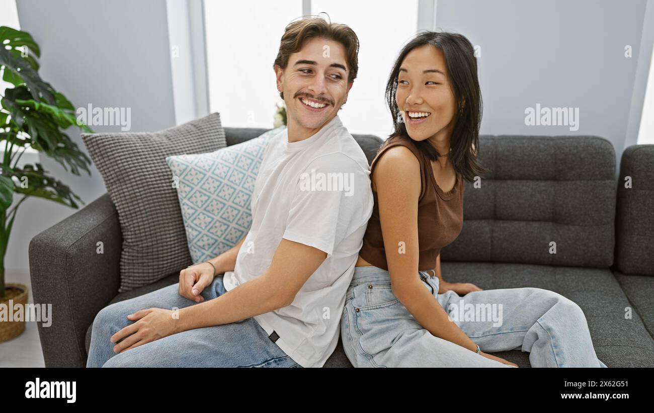 An Interracial Couple Sits Together Smiling In A Cozy Living Room Embodying A Modern Loving